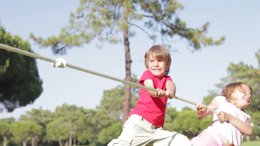 Five Happy Children Pull Rope And Girl Looks At Them Near Flowerbeds In ...