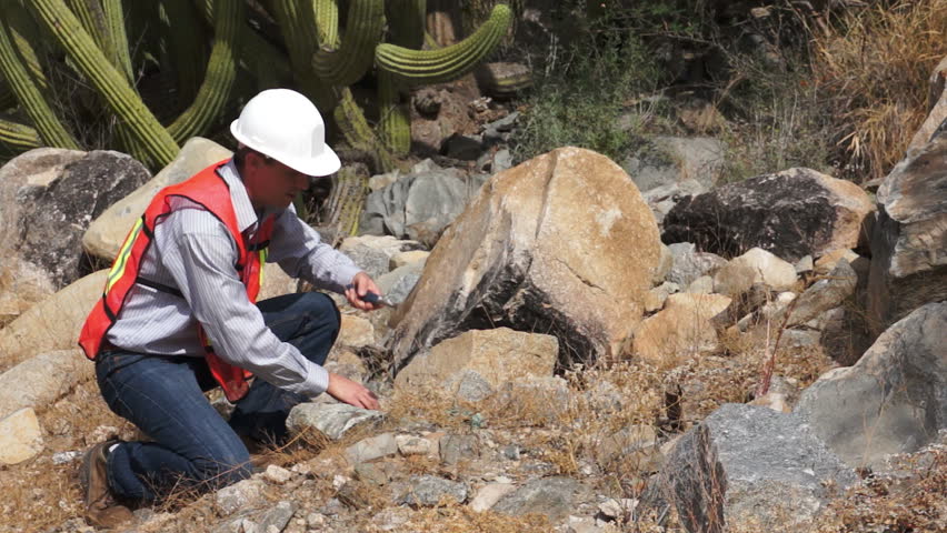 Female Geologist Or Prospector Picks Up A Rock Out In The Field And ...